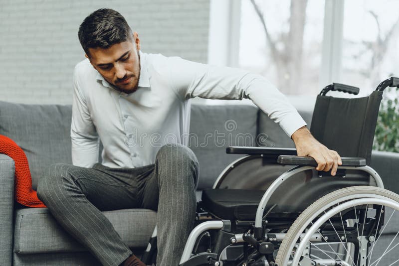 Disabled Man Tries To Sit Down on a Sofa from Wheelchair Stock Photo ...