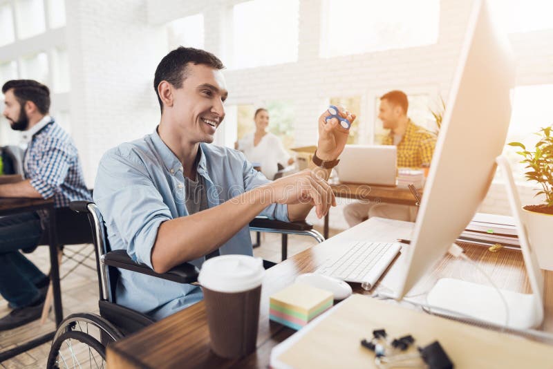 Disabled Person in the Wheelchair Works in the Office at the Computer ...