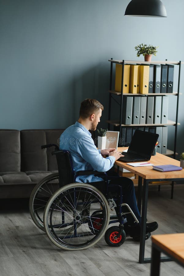Disabled Person in the Wheelchair Works in the Office at the Computer ...