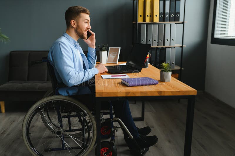 Disabled Person in the Wheelchair Works in the Office at the Computer ...