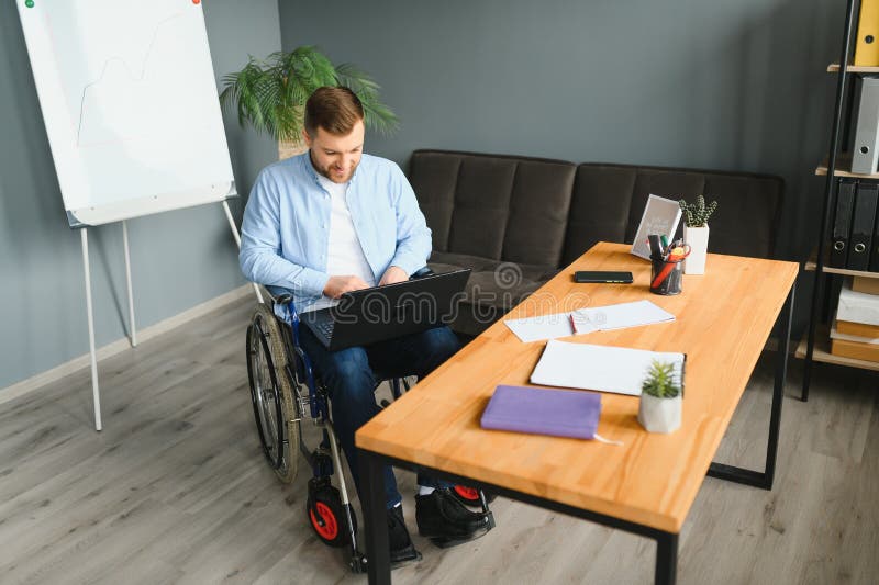 Disabled Person in the Wheelchair Works in the Office at the Computer ...