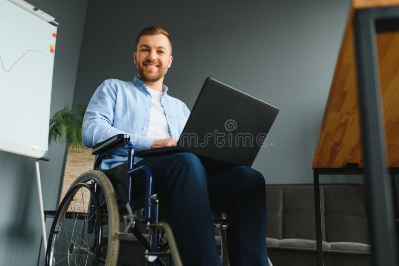 Disabled Person in the Wheelchair Works in the Office at the Computer ...