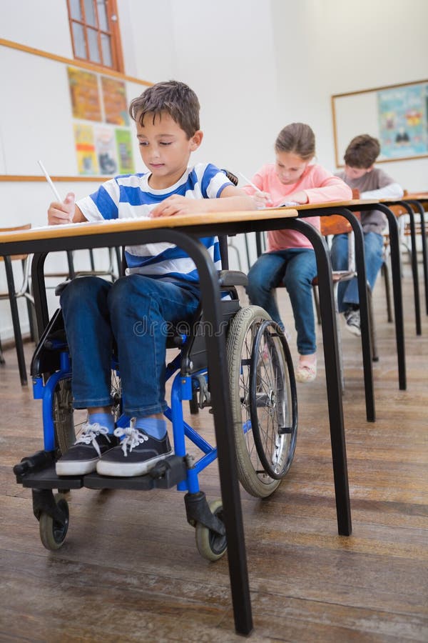 Disabled Pupil Writing at Desk in Classroom Stock Photo - Image of ...