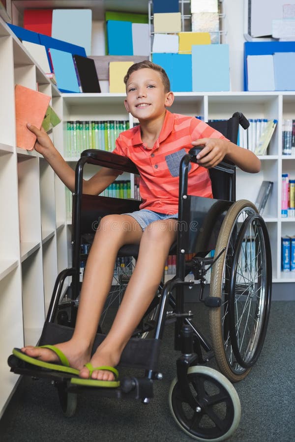 Disabled Schoolboy Selecting a Book from Bookshelf in Library Stock ... Disabled Schoolboy Selecting a Book from Bookshelf in Library Stock ...
