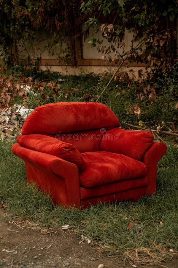 A Discarded Red Couch on Grass by a Brick Wall in a Field Stock Image ...