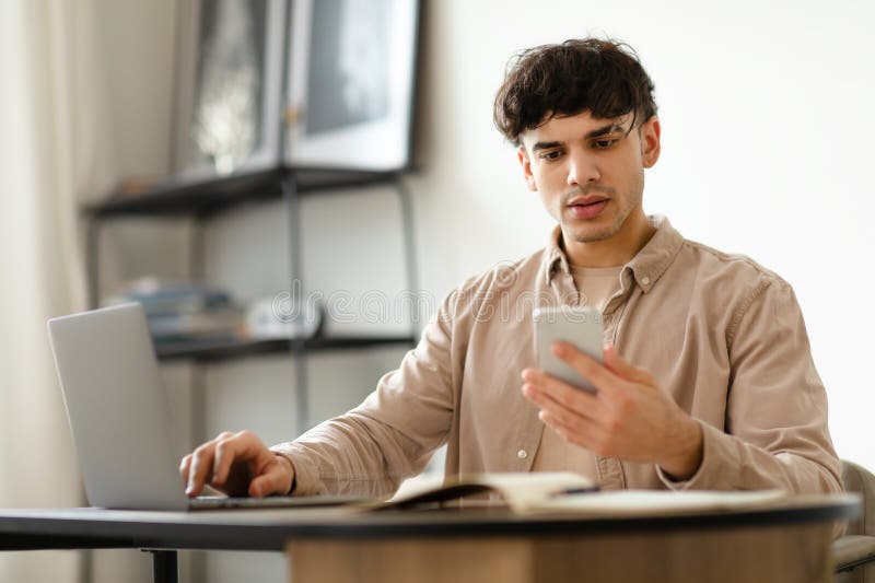 Discontented Arabic Man Using Phone at Workplace Near Laptop Computer ...