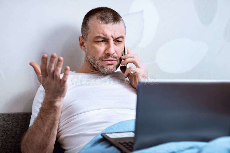 Discontented Man Calling Customer Support Sitting in Bed at Home Stock ...