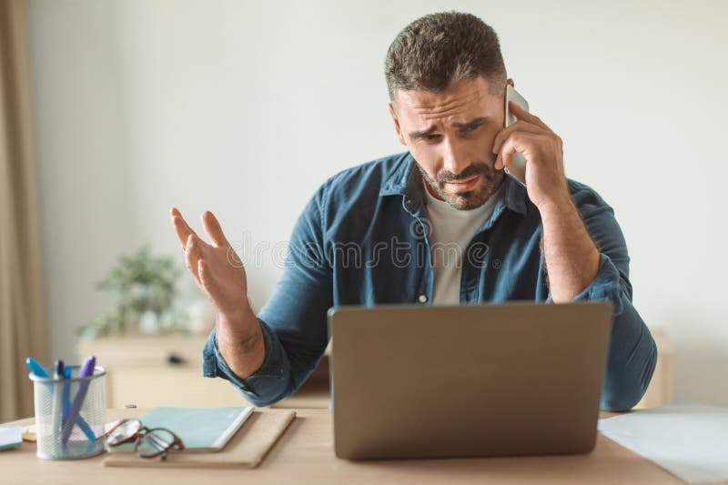 Discontented Middle Aged Guy Talking by Cellphone at Work Desk Stock ...