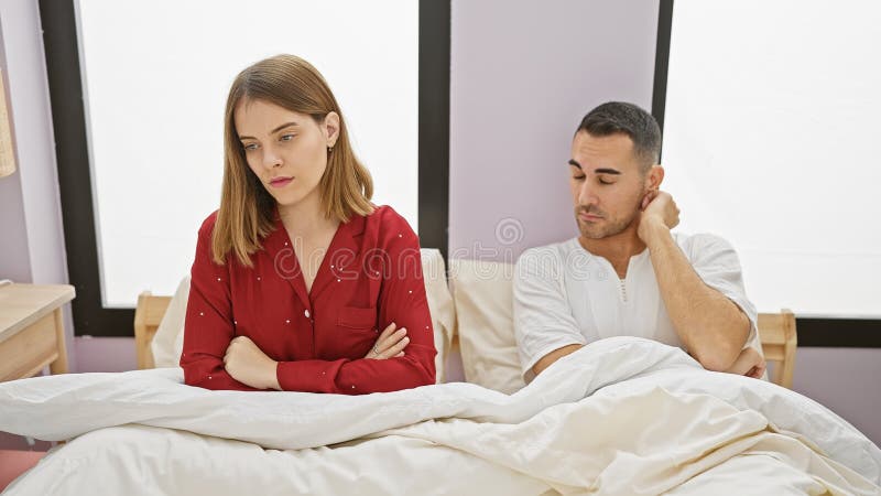 A Discontented Woman and a Man Sit Apart in Bed, Symbolizing ...
