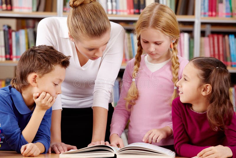 Teacher Reading Book To Children in Library Stock Photo - Image of ...
