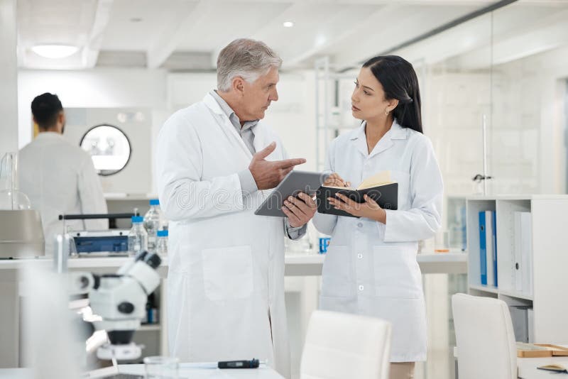 Discussing the New Data Recorded. Two Scientists Using a Digital Tablet ...
