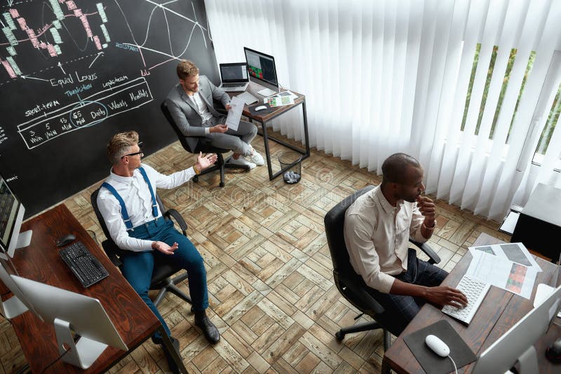 Discussing Strategies. High-angle View of Three Traders Sitting by ...
