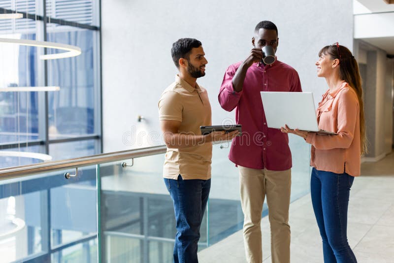 Discussing Work, Colleagues Using Laptop and Tablet while Standing in ...