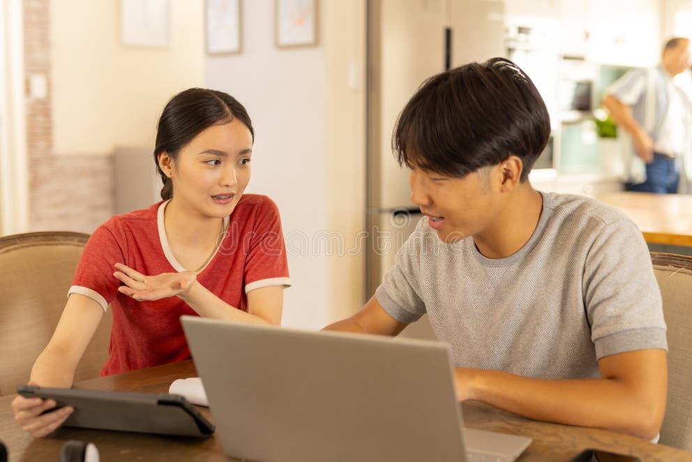 Discussing Work, Young Asian Brother and Sister Using Laptop and Tablet ...
