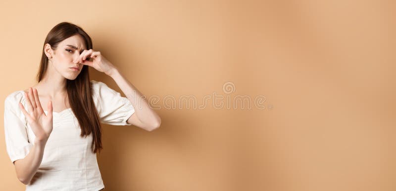 Displeased Woman Plug Her Nose From Bad Smell Showing Stop Gesture And