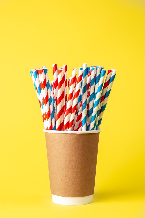 Disposable Paper Cup with Striped Paper Straws on a Yellow Background ...