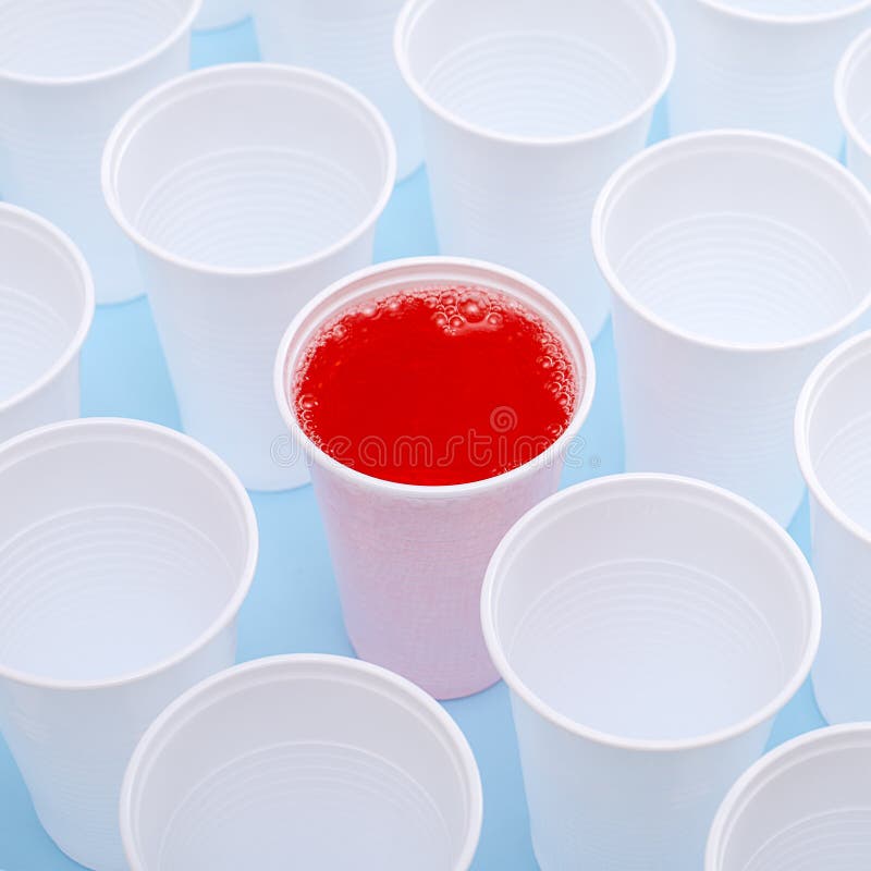 Disposable Plastic White Empty Cups on and One Glass Filled with Red ...
