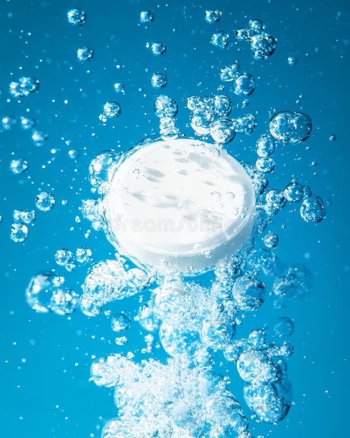 Dissolving White Tablet Creates Bubbles in Vivid Blue Water Background ...