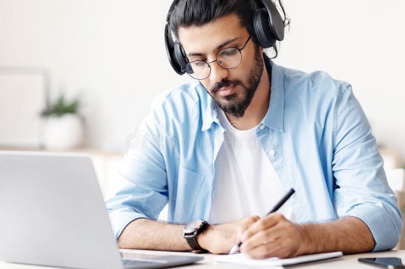 Distance Learning. Young Arab Guy in Headphones Studying with Laptop at ...