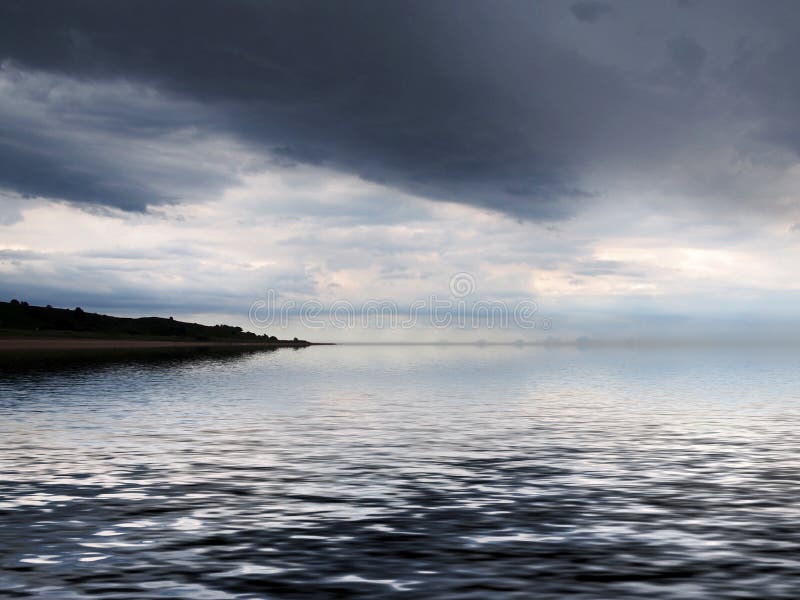 Distant Coast Reflected in the Sea with Dramatic Dark Storm Clouds ...