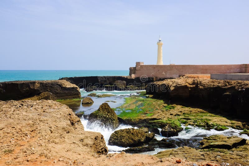 A Distant Lighthouse with Rocks and Ocean Stock Image - Image of africa ...