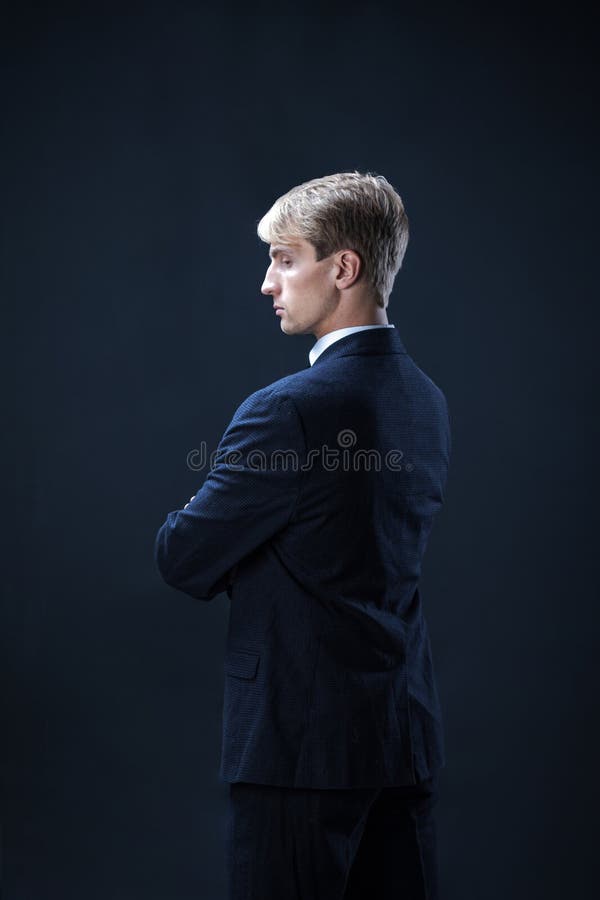 Distinguished Figure Stands Confidently in a Navy Suit Against a Dark ...