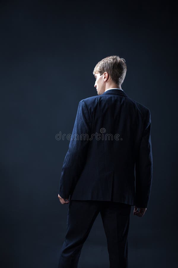Distinguished Figure Stands Confidently in a Navy Suit Against a Dark ...