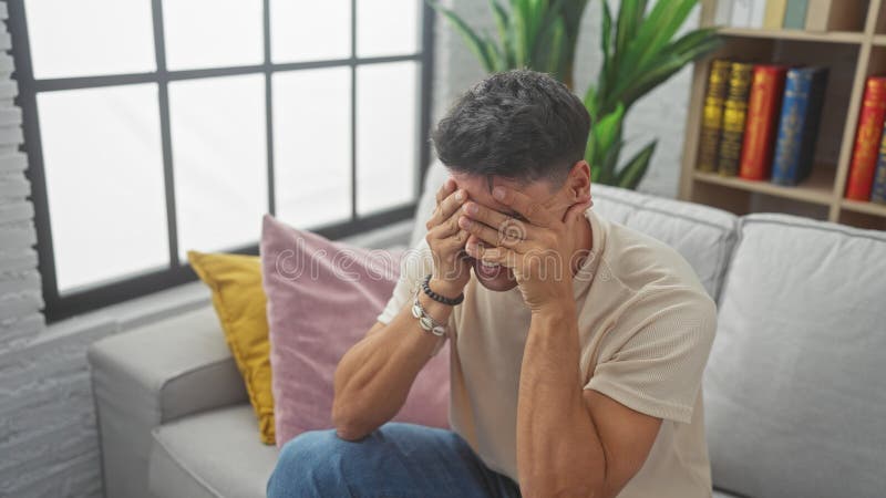 A Distressed Hispanic Man Covering His Face with Hands while Sitting on ...