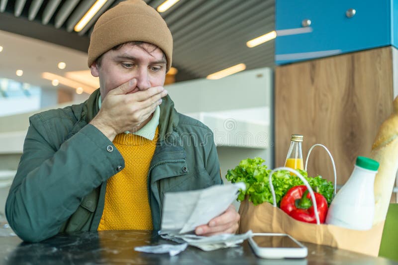 Distressed Man Examining Receipt, with Groceries on Table, in Cafe ...