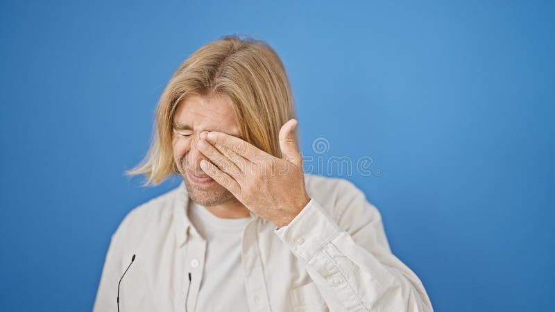 A Distressed Man Facepalming Against a Blue Background, Embodying ...