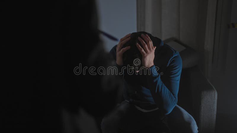 A Distressed Man Sits Indoors with His Head in His Hands, Suggesting an ...