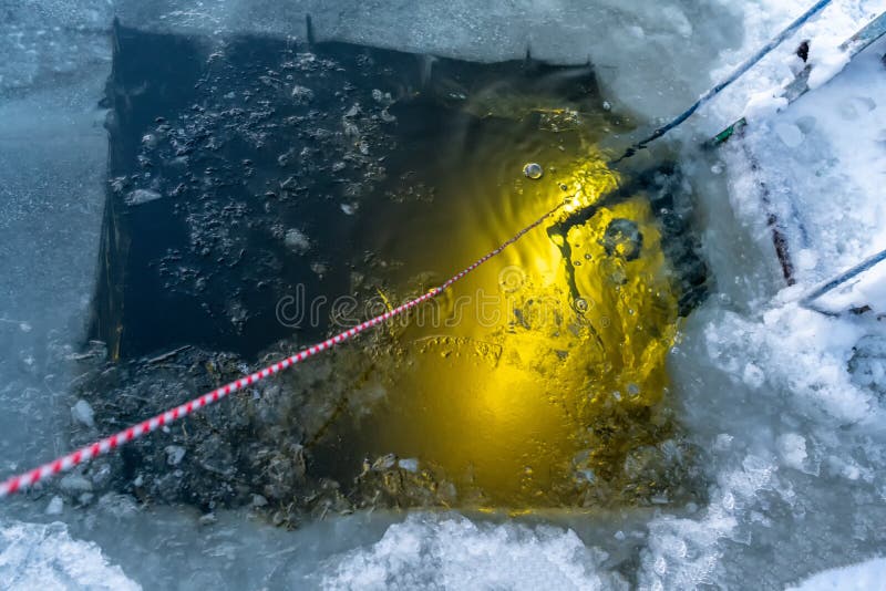A Diver from Under the Water Shines with a Flashlight Torch an Ice Hole ...