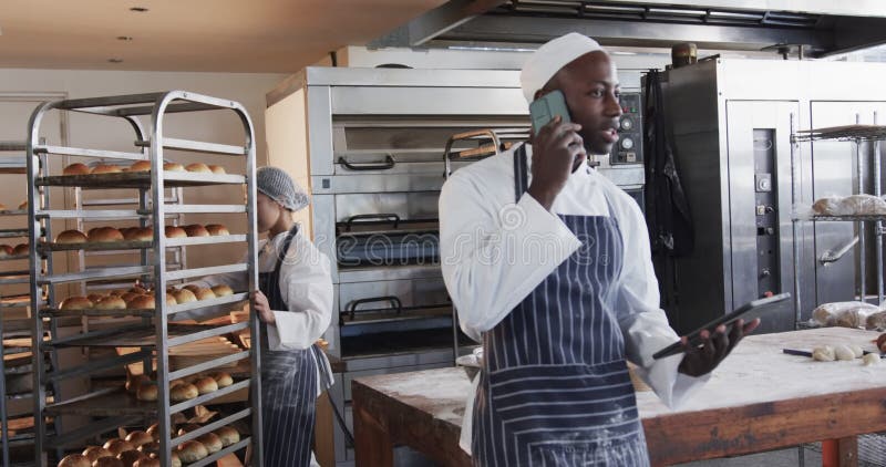 Diverse Bakers in Bakery Kitchen, Talking on Smartphone and Holding ...
