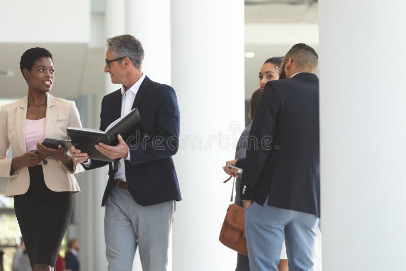 Diverse Business People Interacting with Each Other while Walking in ... Diverse Business People Interacting with Each Other while Walking in ...
