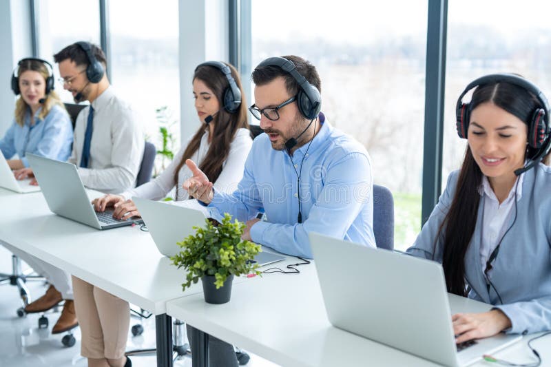 Diverse Call Center Workers Sitting in Row and Communicating with ...