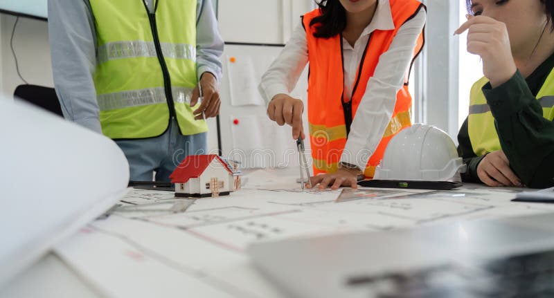 Construction Team Analyzing Blueprints with a House Model and Measuring ...