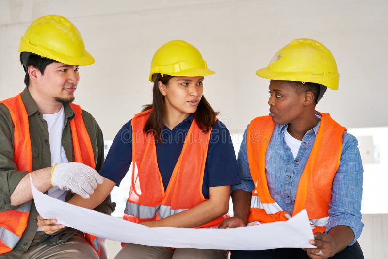 Diverse Construction Workers Discussing while Examining Blueprint of ...