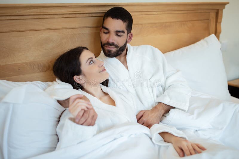 Diverse Couple In Love Embracing Lying In Bed Indoors Stock Image