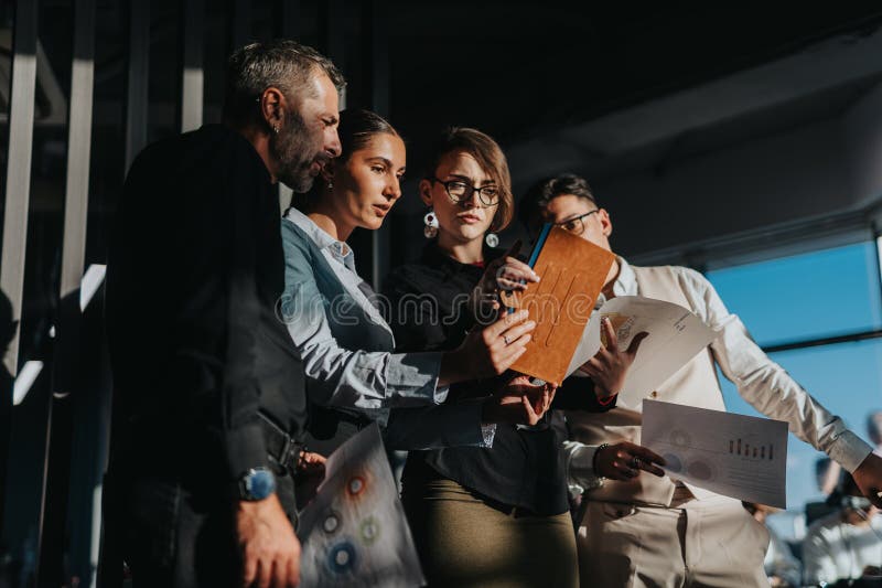 A Diverse Group of Business People Analyzing Documents and Data Charts ...