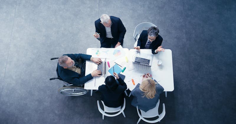 Diverse Group of Business Professionals Sits at Table Talking Stock ...