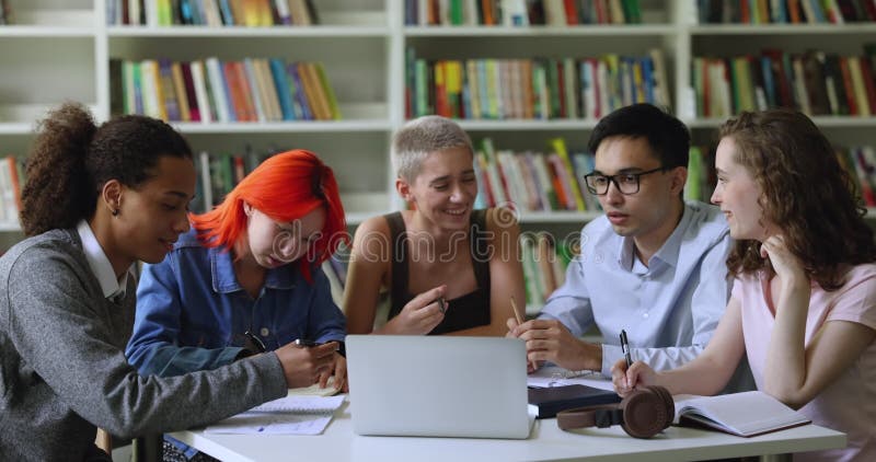 Diverse Group of Students Studying Together Reading Book and Talking ...