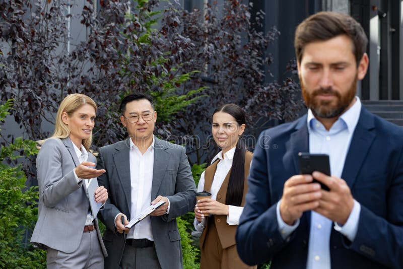 Diverse Group of Colleagues Standing Behind Man with Cell Phone in ...