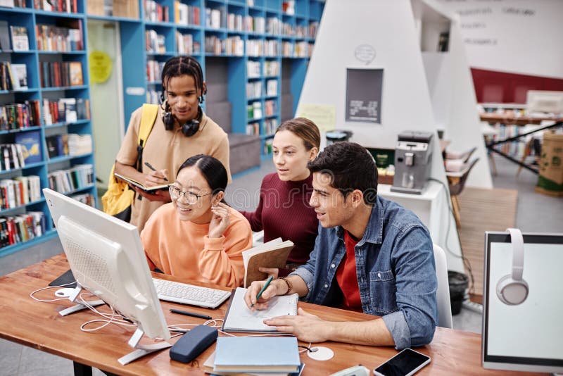 Diverse Group of College Students Using Computer Together in Library ... Diverse Group of College Students Using Computer Together in Library ...