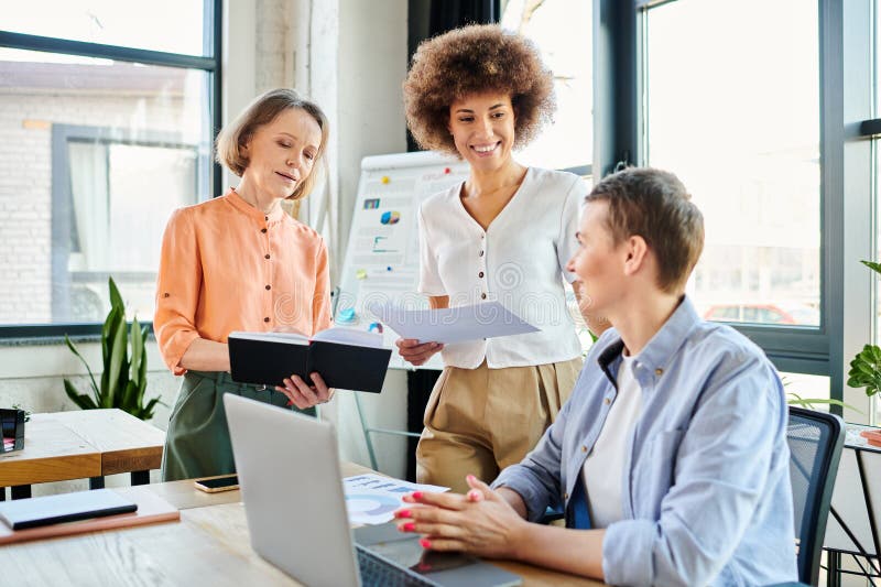 Diverse Group of Hardworking Businesswomen Gathered Around a Laptop in ... Diverse Group of Hardworking Businesswomen Gathered Around a Laptop in ...