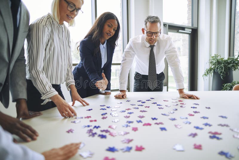 Smiling Businesspeople Solving a Puzzle on an Office Table Stock Image ...