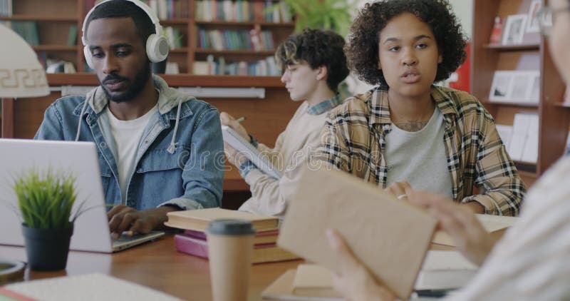 Diverse Group of Students Doing Assignments in Library Reading Books ...