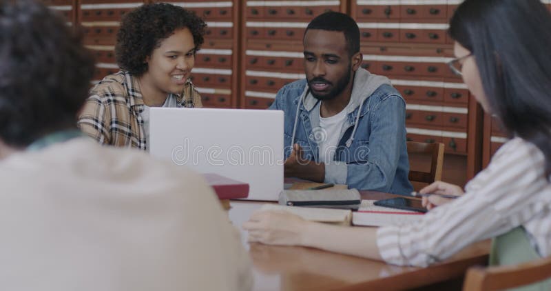 Diverse Group of Students Doing Research in Library Using Laptop ...