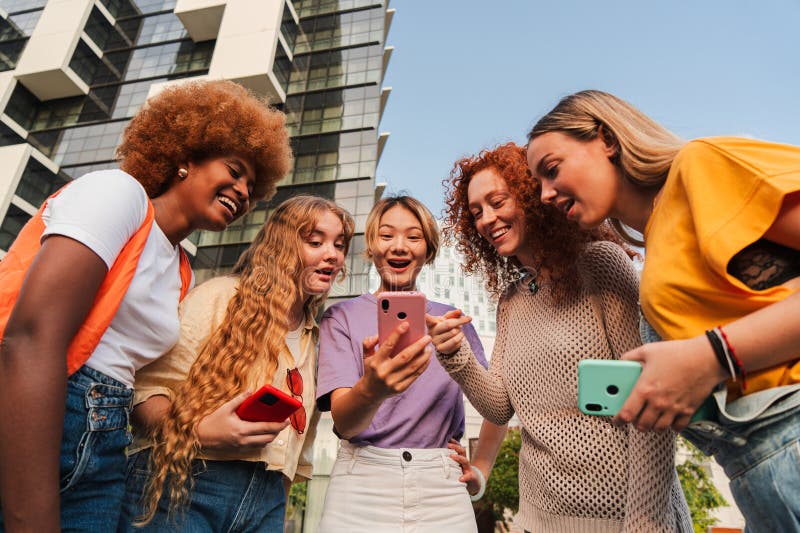Diverse Group of Young Women Excitedly Using a Smartphone Outdoors ...