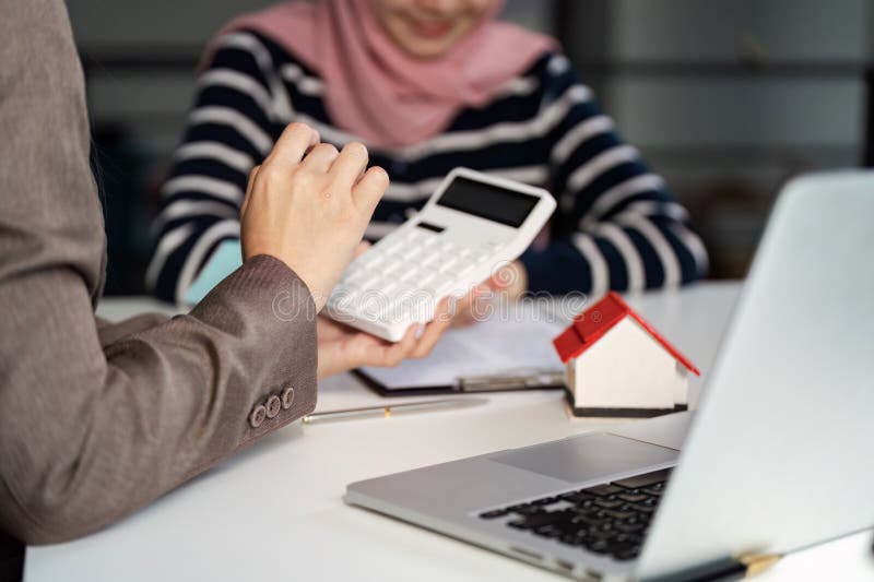 Diverse Real Estate Agent Explaining Financial Calculations To Client Using Calculator in Modern ...