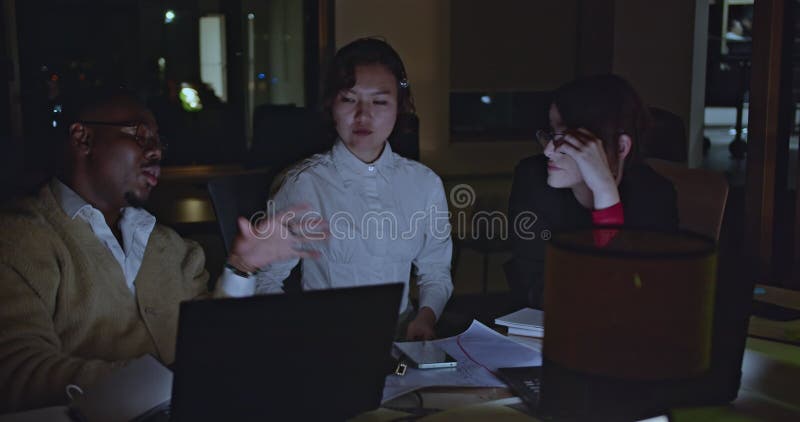 Diverse Team Collaborates on a Project Late at Night in a Modern Office ...